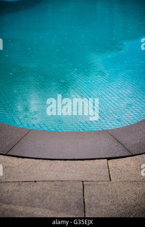 Curved turquoise swimming pool in front of traditional white villa in ...