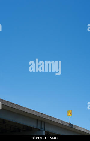 A yellow 45mph Freeway Exit Sign with trees and blue skies shot from a ...
