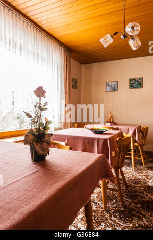 Hostel dining room interior with tables and chairs along white wall ...