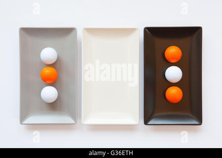 Different ceramic dishes with golf balls on over white background ...