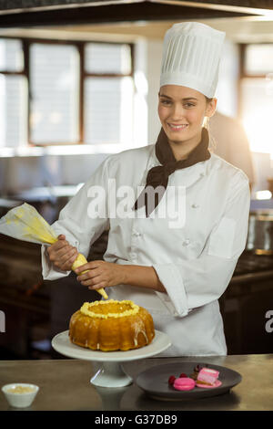 Portrait of smiling chef piping icing on cake Stock Photo - Alamy
