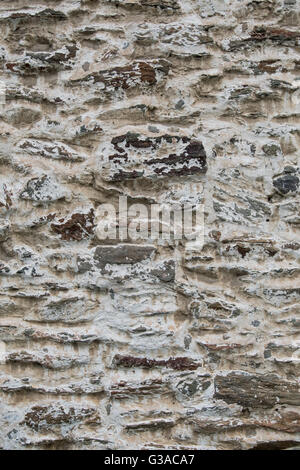 Gray exterior wall with washed plaster and a small window made of glass ...