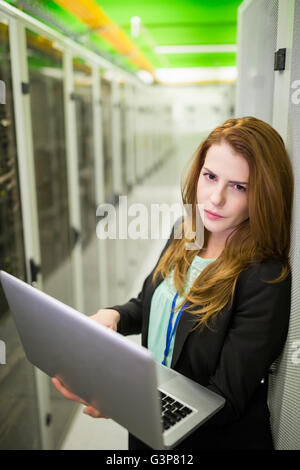 Technician using laptop in server room Stock Photo - Alamy