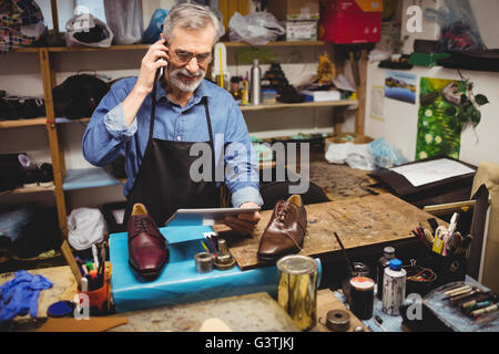 Cobbler calling with his mobile phone Stock Photo - Alamy