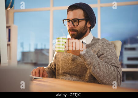Hipster drinking coffee front of computer Stock Photo - Alamy