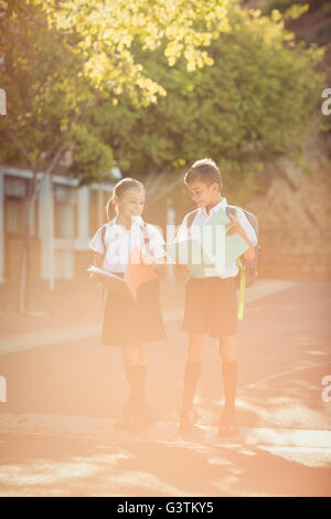 School kids reading books while walking in corridor Stock Photo - Alamy