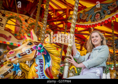 An attractive blond girl riding a carousel on the South Bank in London ...