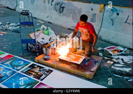 Street Artist creating a painting of the Colosseum using stencils and ...