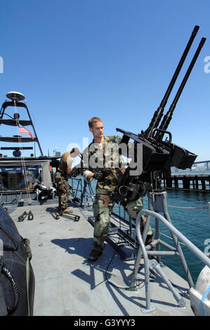 Two gun crewmen in front of a stand of 155 mm projectiles, including ...
