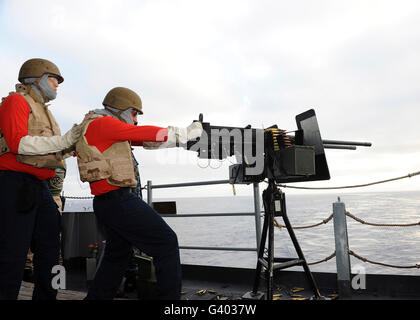 US Navy Aviation Ordnanceman fires .50 cal machine gun at a floating ...