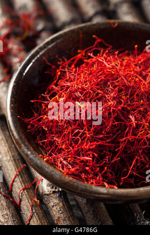 Raw Organic Red Saffron Spice in a clay bowl on wooden table Stock ...
