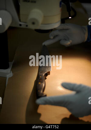A forensic scientist collects blood and fibers from an item of clothing ...
