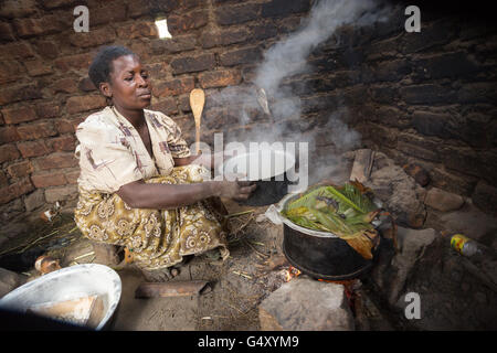 Woman cooking over an open fire in her basic rural village kitchen ...