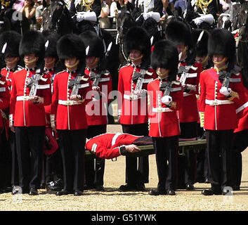 A fainting Guardsman is carried off the parade ground as The Queen ...