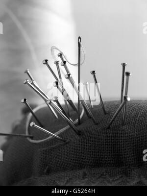 Pins and Needles in a pin cushion with thread going through the needle ...