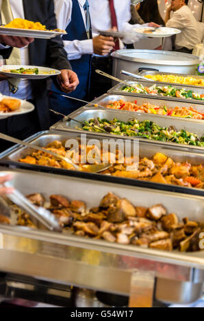 People help themselves to food at a self-service buffet at a party ...