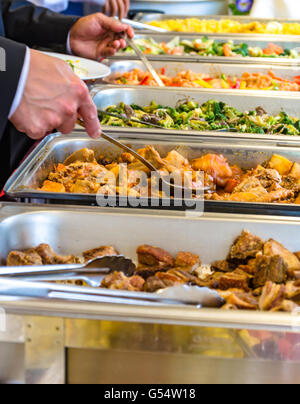 People help themselves to food at a self-service buffet at a party ...