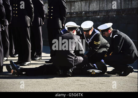 Naval officers attend to another officer who collapsed during a passing ...