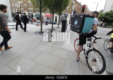 Deliveroo food delivery cyclist wearing a large branded backpack ...