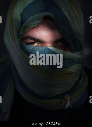A Syrian refugee named only as Nidal, his face covered to protect his ...