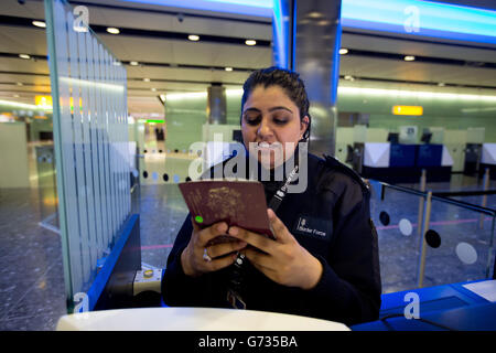 A Border Force officer checks passports of arrival passengers in ...