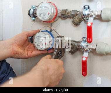Male plumber fixing water meter with adjustable wrench Stock Photo - Alamy