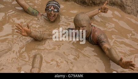 Having fun at Tough Mudders. Mud Mile obstacle, man jumping off mud ...