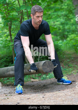 Man lifting log in the forest Stock Photo - Alamy