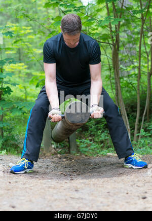 Man lifting log in the forest Stock Photo - Alamy