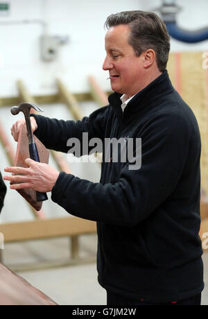 Prime Minister David Cameron fixes tiles to a roof mockup during a ...