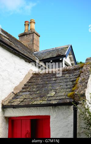 Typical Scottish cottage with red door and weathered slate roof in the ...