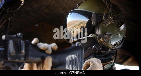A crewman on board a Royal Air Force Puma helicopter mans a machine gun ...