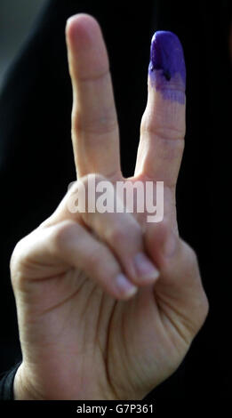 An Iraqi Woman gives the victory sign with a purple finger, indicating ...