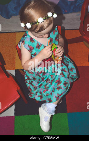 smiling girl in bright dress and sun hat drinking water on warm summer ...