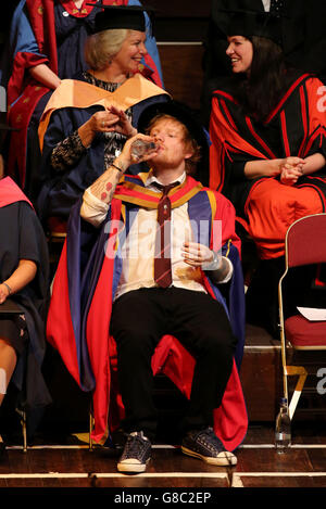 Singer songwriter Ed Sheeran drinks from a cup while being encouraged ...