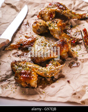 Spicy fried chicken wings in paprika sauce in a black plate on a dark ...