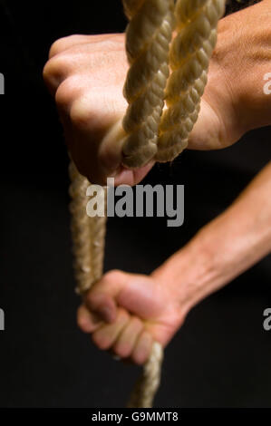 the hands of men squeezed a thick rope Stock Photo - Alamy