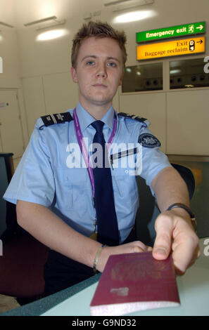 An Immigration officer wearing a new uniform checks a passport from a ...
