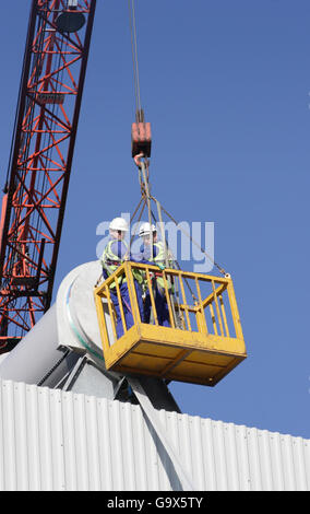 Two workmen access the roof of an industrial plant using a cradle ...