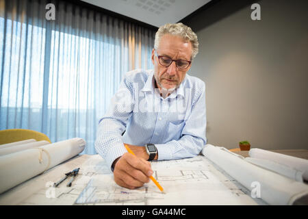Mature man architect working on tablet at desk indoors in office ...