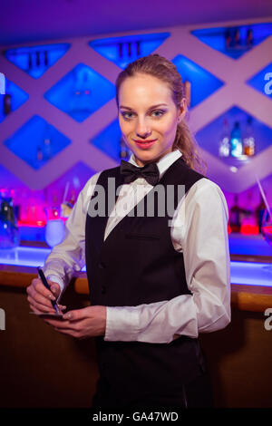 Beautiful confident young female barkeeper standing while straining ...