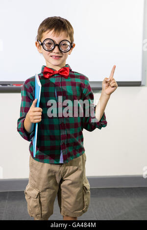 Cute Schoolboy Raising Hand In Classroom Stock Photo - Alamy