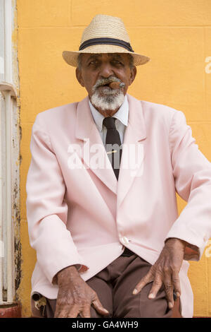 Well-dressed Cuban gentleman in pink blazer with tie sitting outdoors ...