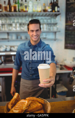Cheerful male barista offering coffee in cafe Stock Photo - Alamy