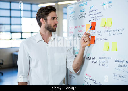 Young man pointing at sticky note with text DAY OFF on alarm clock ...