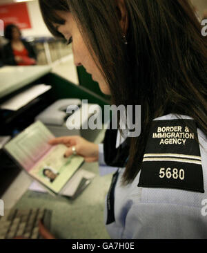An Immigration officer wearing a new uniform checks a passport from a ...