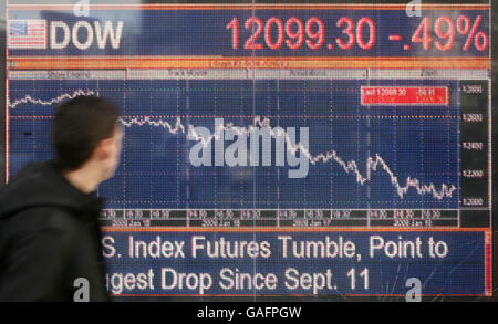 A man walks past a screen showing Japan's Nikkei 225 index at a ...