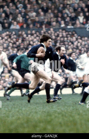 Scotland's Andy Irvine (c) makes a break with the ball, supported by ...