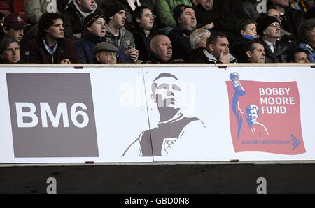 A advertisment promotes the Bobby Moore Fund, as fans watch the match ...