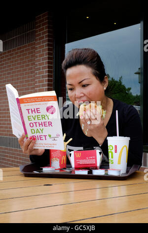 young female reading dieting book while drinking beer in a pub garden ...